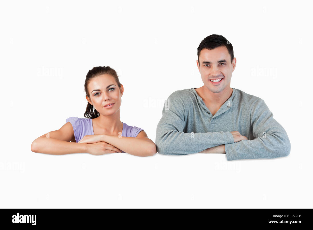 Smiling young couple looking over a wall Stock Photo - Alamy