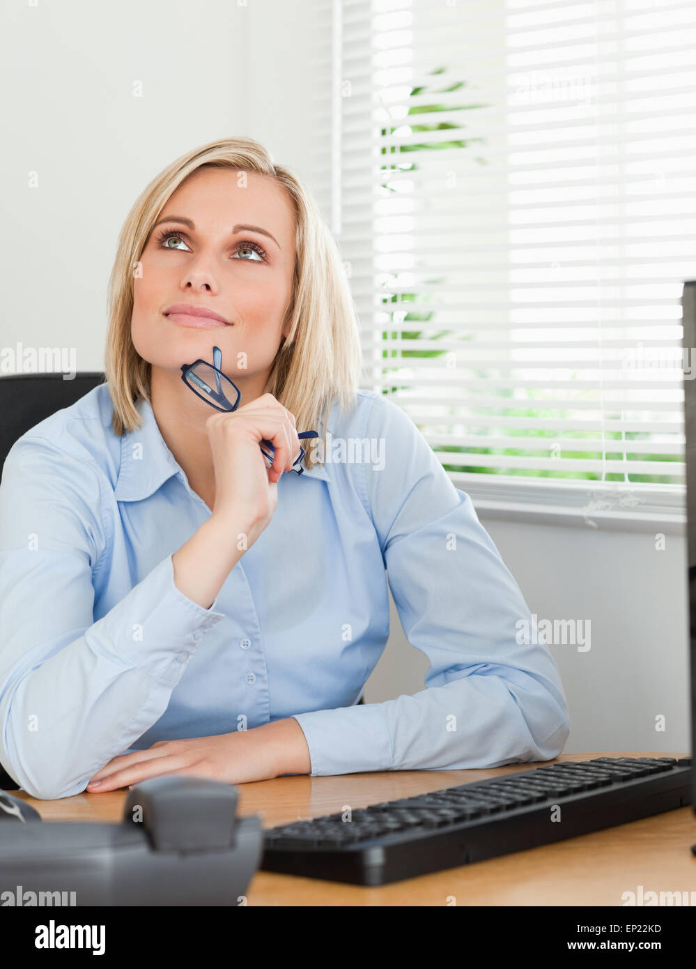Thinking beauty behind a desk looking at the ceiling Stock Photo - Alamy