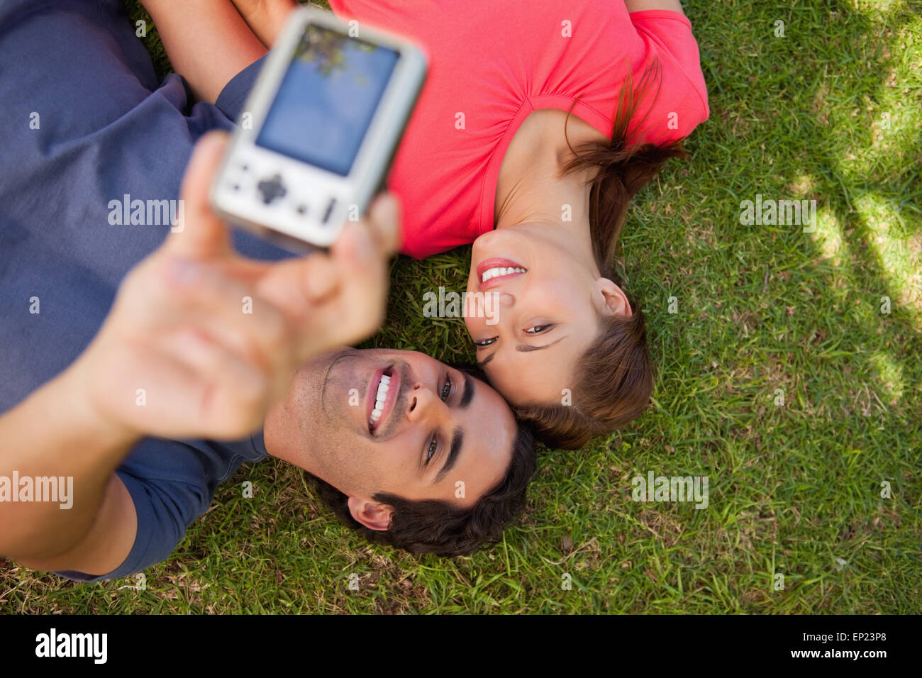 Two friends using a camera while lying side by side Stock Photo - Alamy