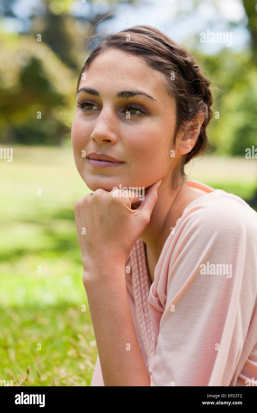 Woman looking into the distance while resting her head on her fist ...