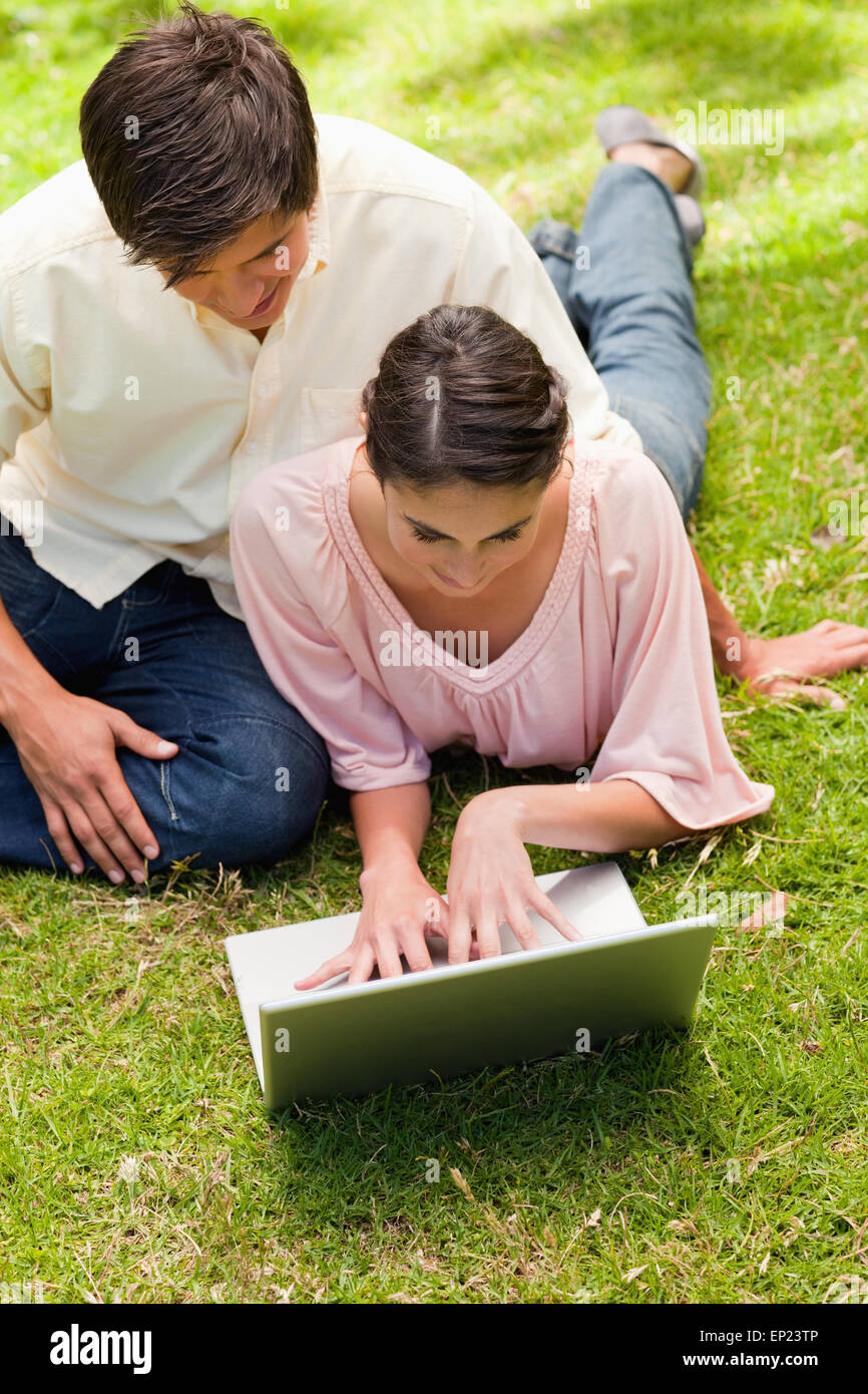 Two friends looking into a laptop together while lying down Stock Photo ...