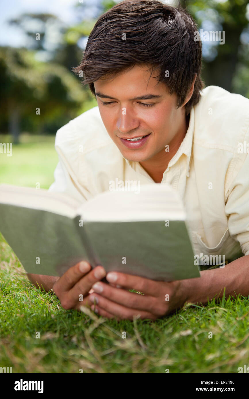Man smiling while reading a book as he lies down Stock Photo - Alamy
