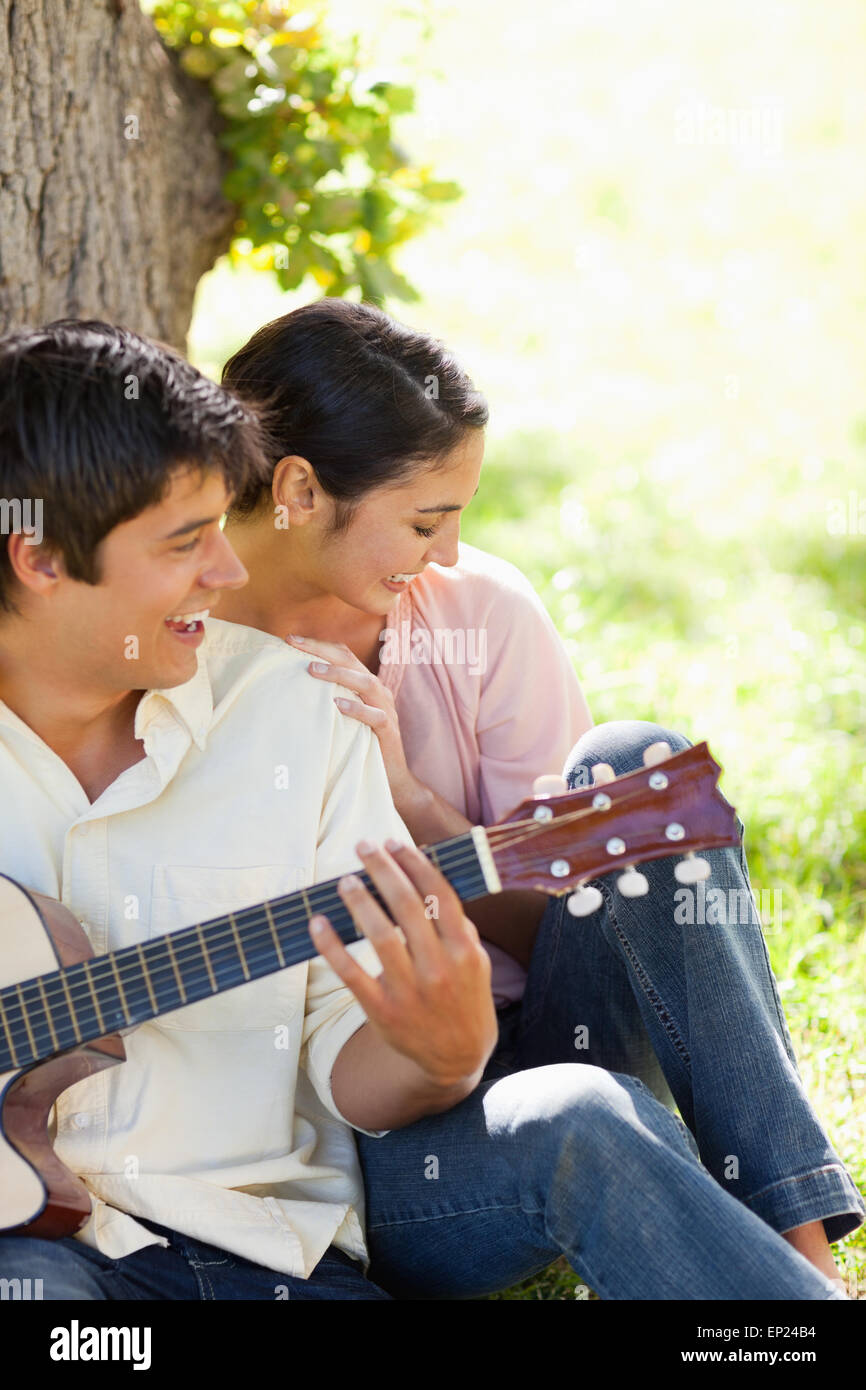 Woman laughing with her friend who is playing the guitar Stock Photo ...