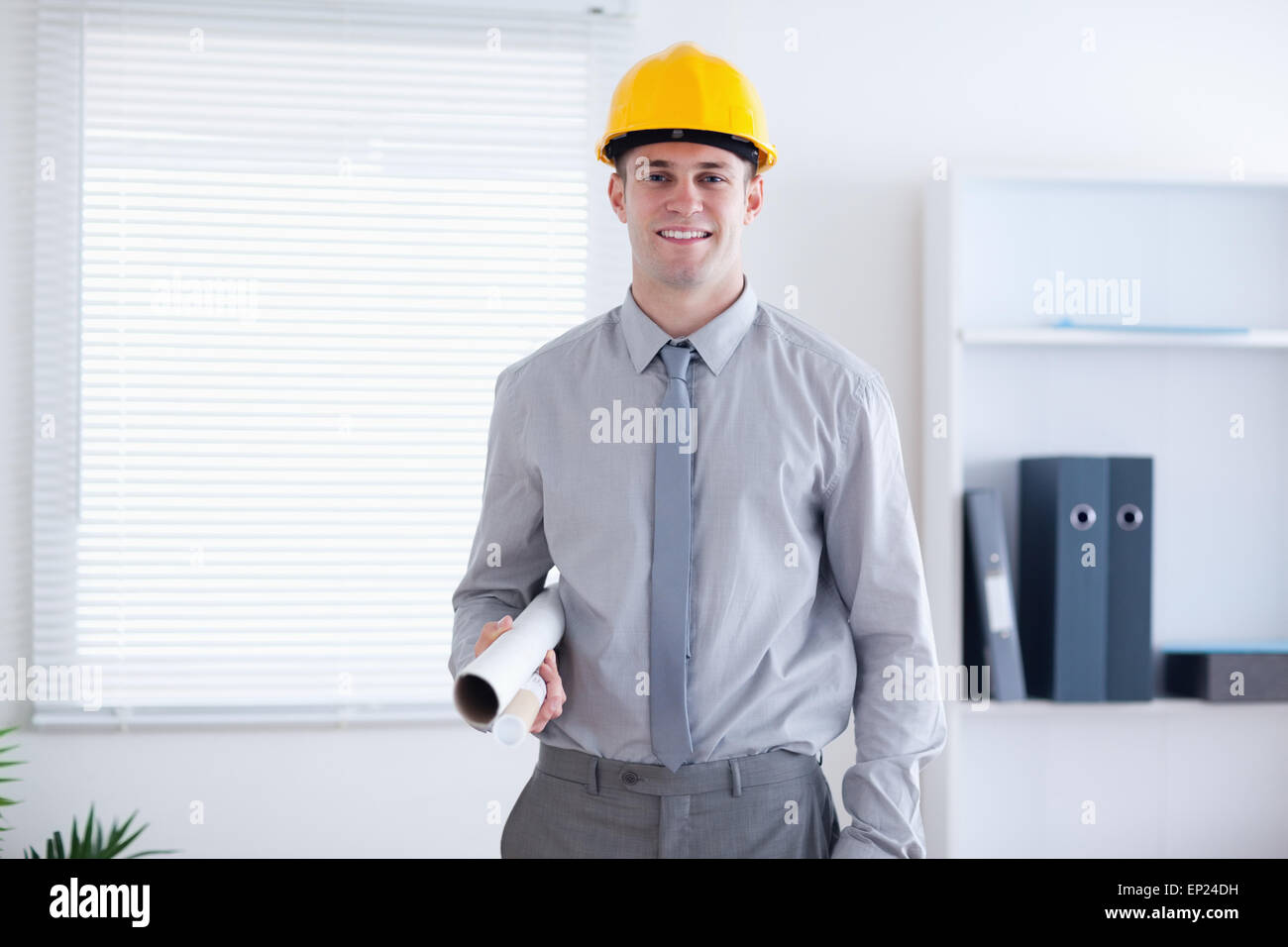 Architect wearing helm and carrying plans Stock Photo - Alamy