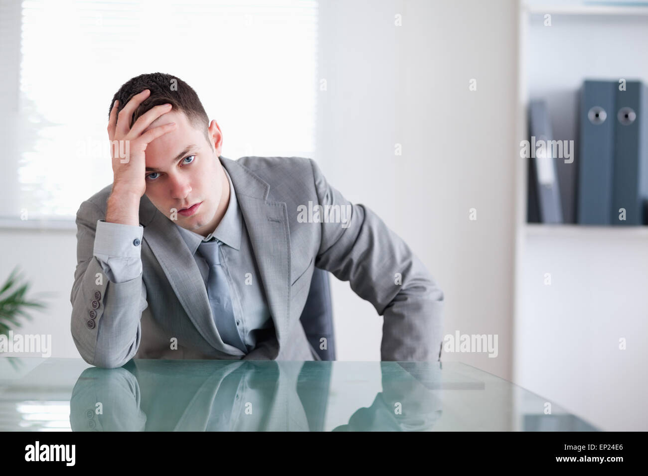 Disappointed businessman sitting behind a table Stock Photo - Alamy