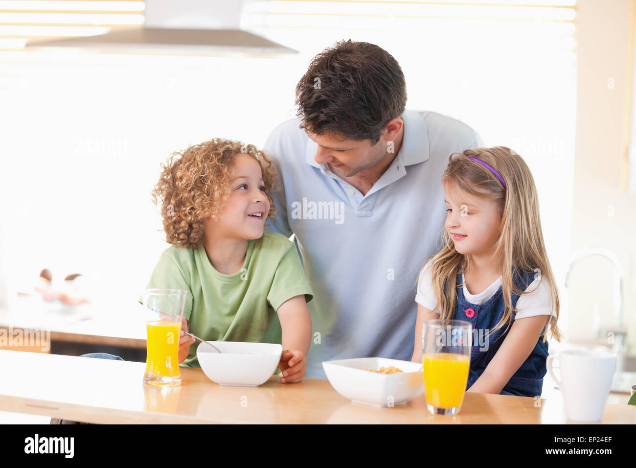 Smiling father with his children having breakfast Stock Photo - Alamy