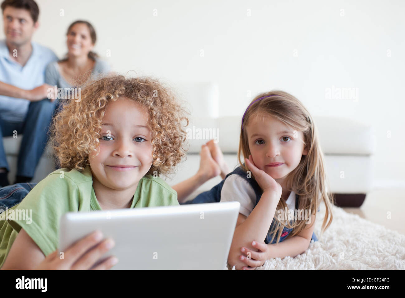 Happy children using a tablet computer while their happy parents are ...