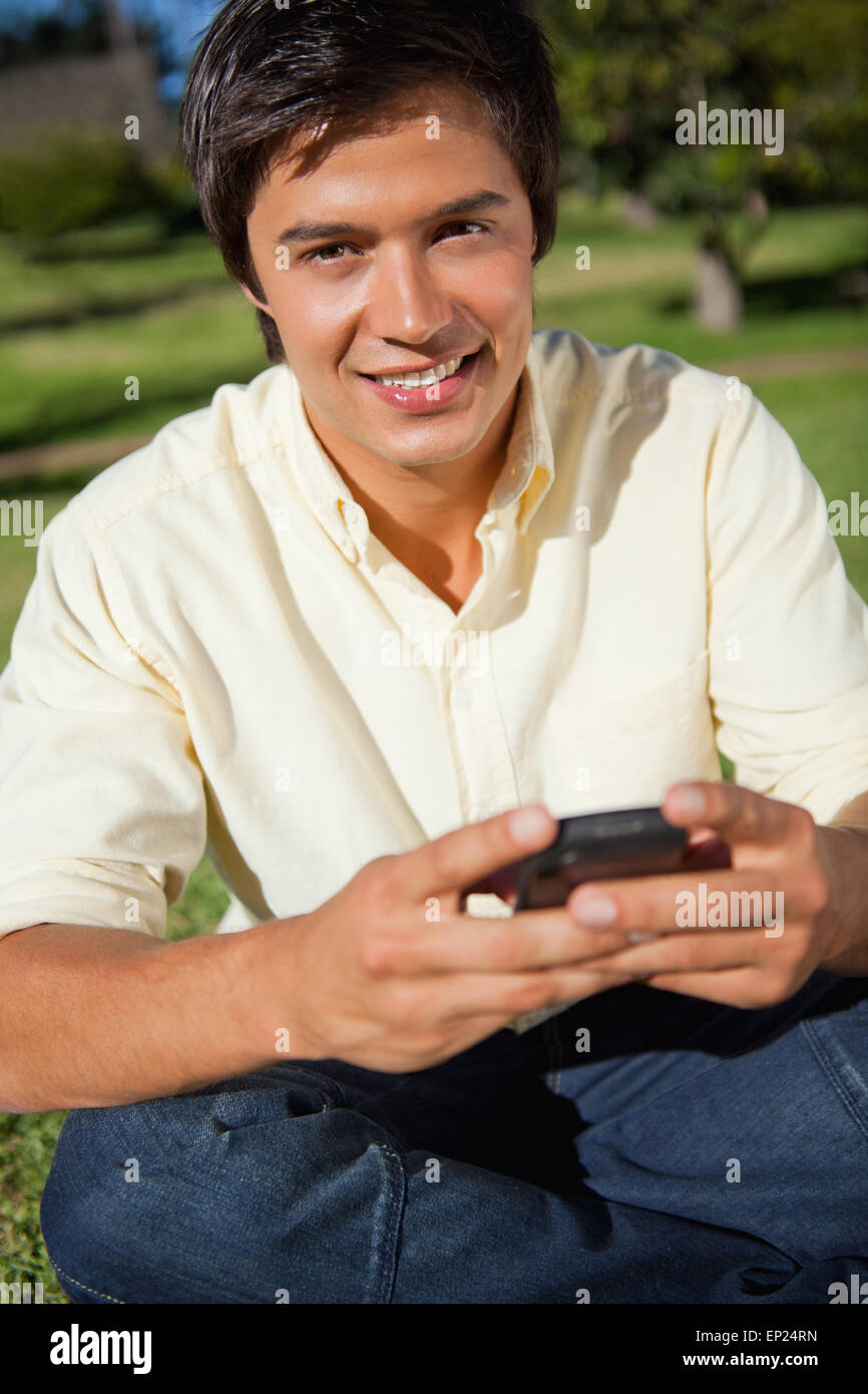 Man looking ahead while writing a text message as he is sitting down ...
