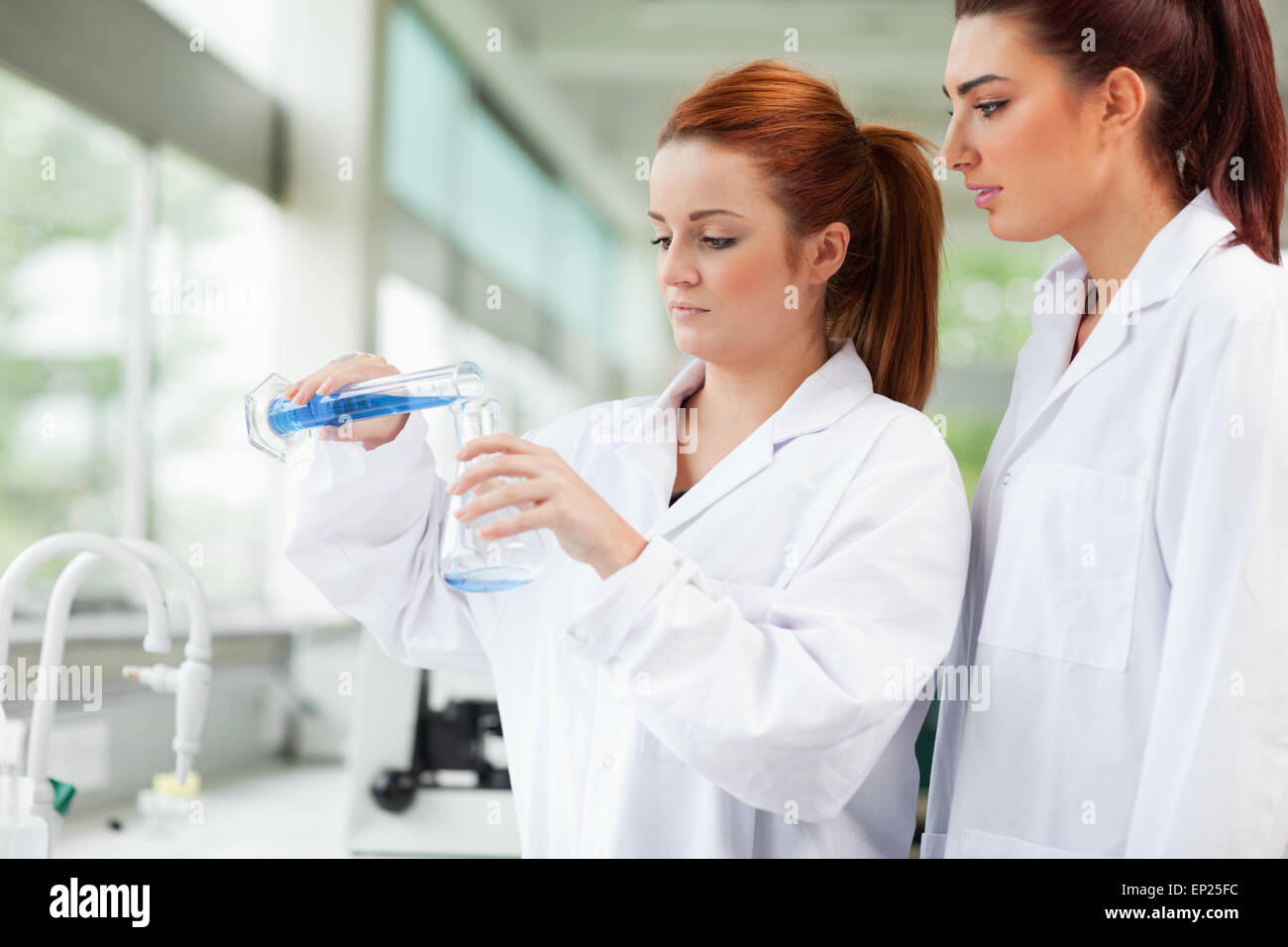 Cute scientists pouring liquid in an Erlenmeyer flask Stock Photo - Alamy