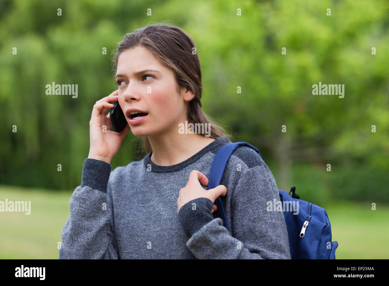 Young calm girl talking on the phone while looking towards the side ...