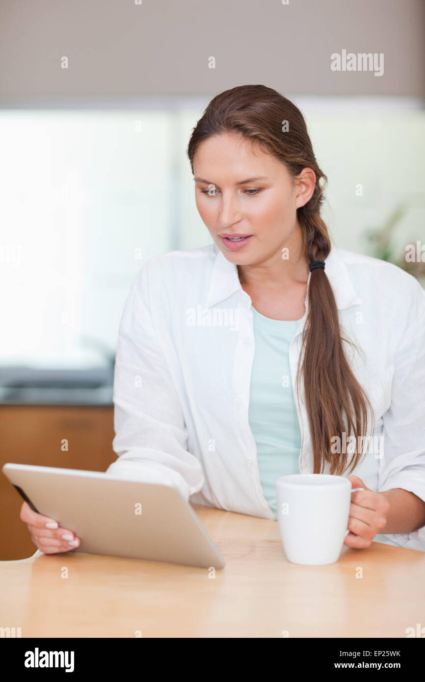 Portrait of a woman using a tablet computer while drinking tea Stock ...