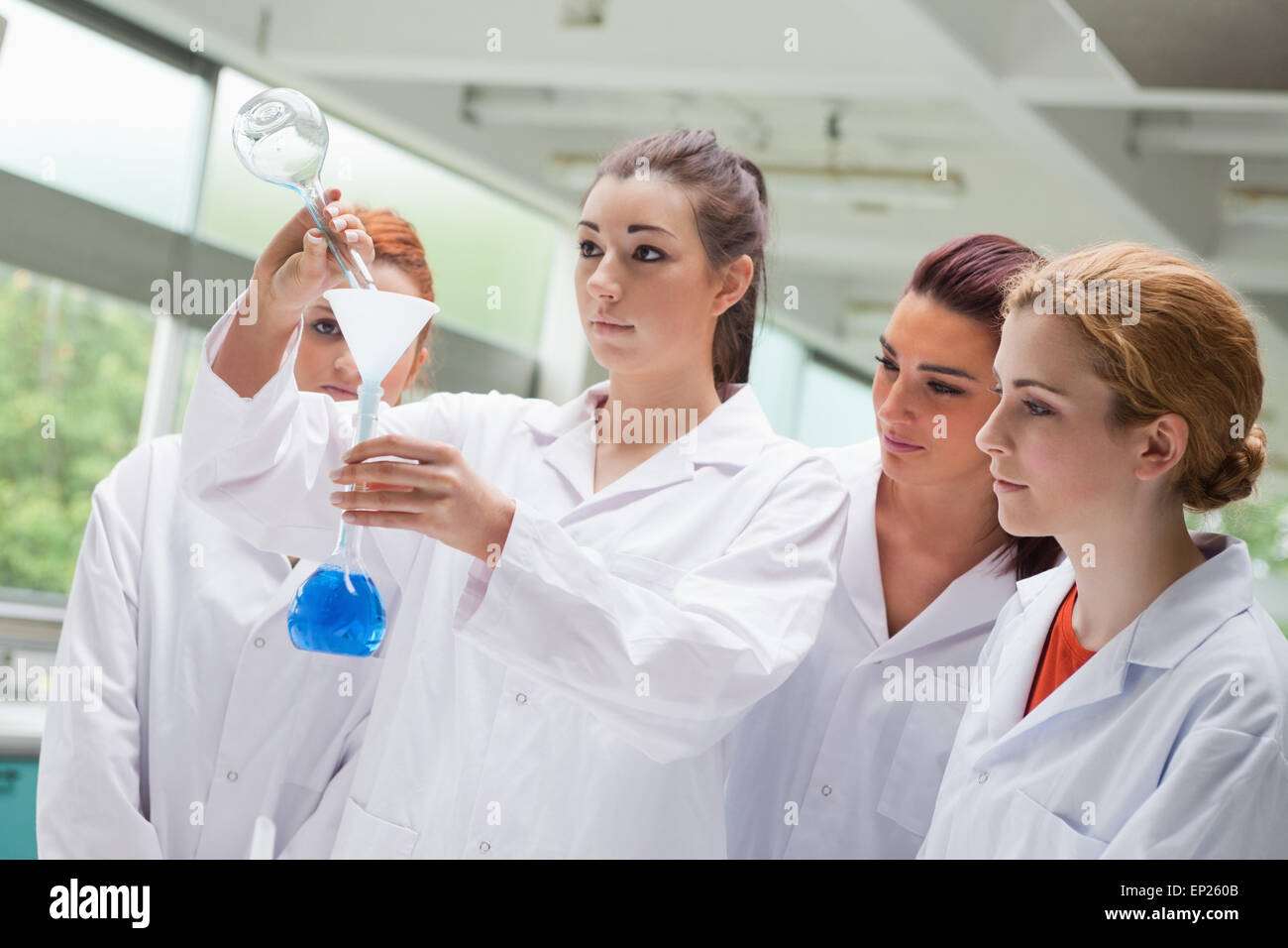 Cute science students pouring liquid in a flask Stock Photo - Alamy