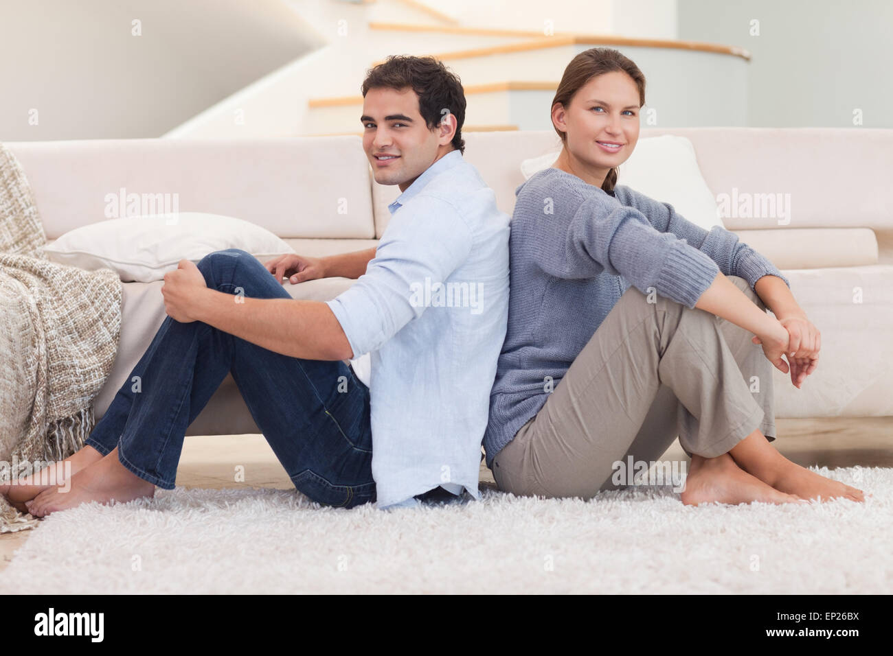 Young couple sitting back to back Stock Photo - Alamy