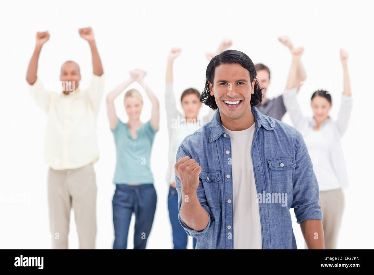 Close-up of a man clenching his hand with people raising their arms ...