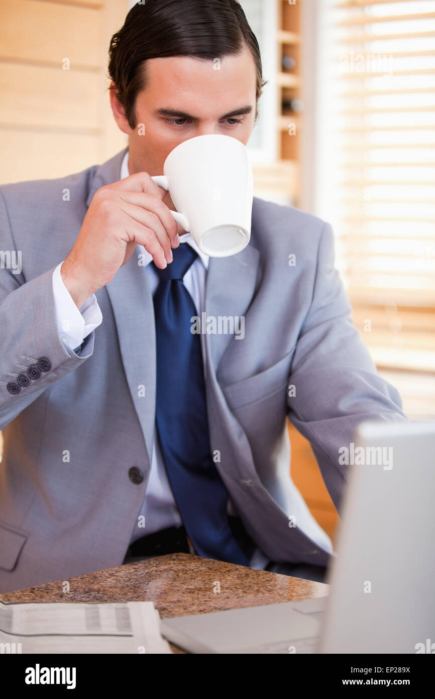 Businessman taking a sip of coffee next to his laptop Stock Photo - Alamy