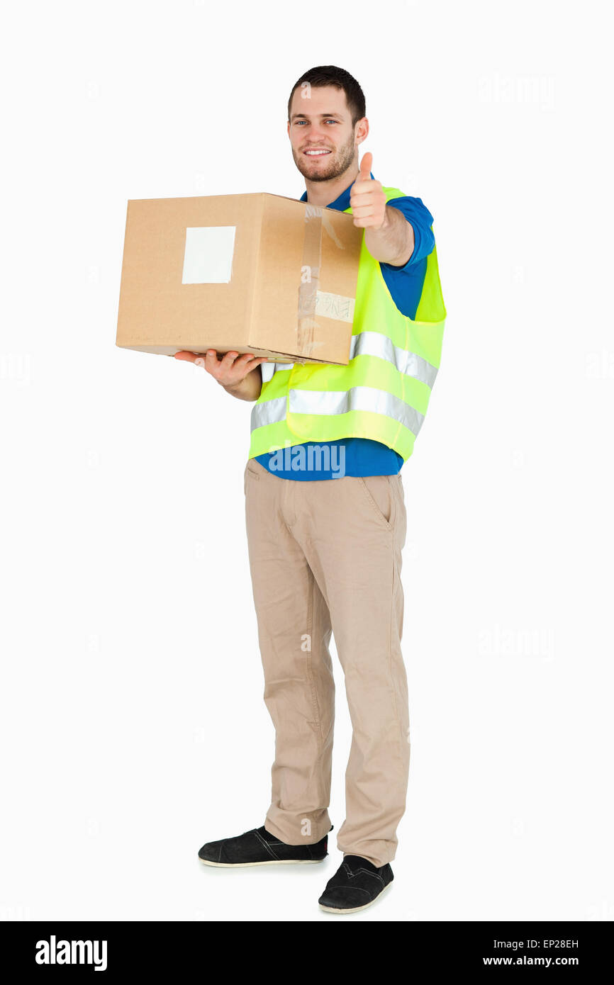 Smiling young delivery man giving thumb up while holding parcel Stock ...
