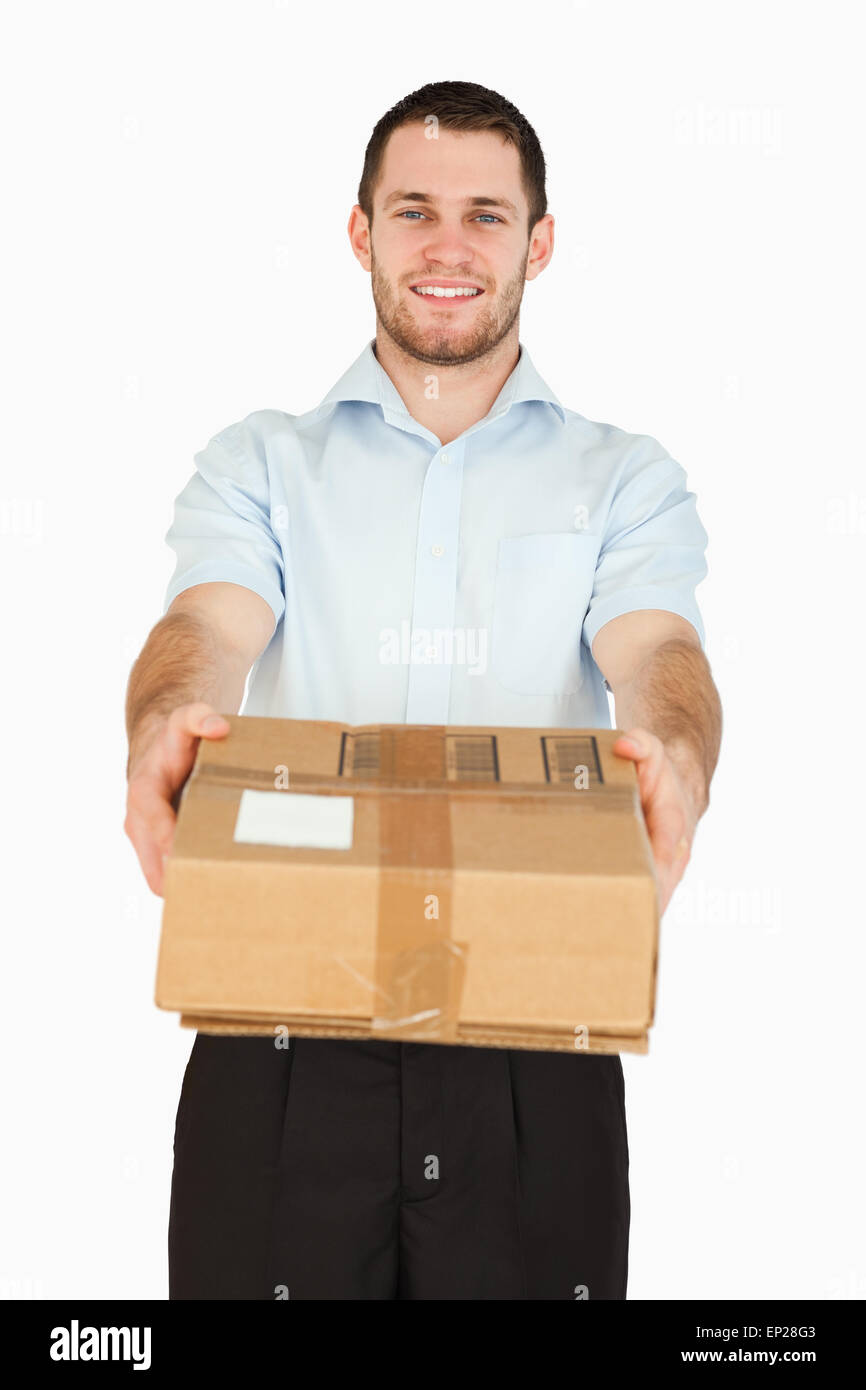 Smiling young post employee handing over parcel Stock Photo - Alamy