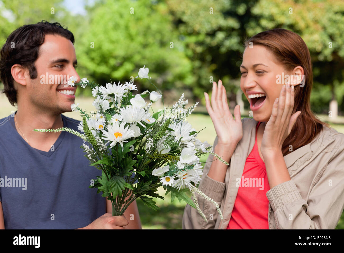 Woman laughing excitedly as she is presented with flowers by her friend ...