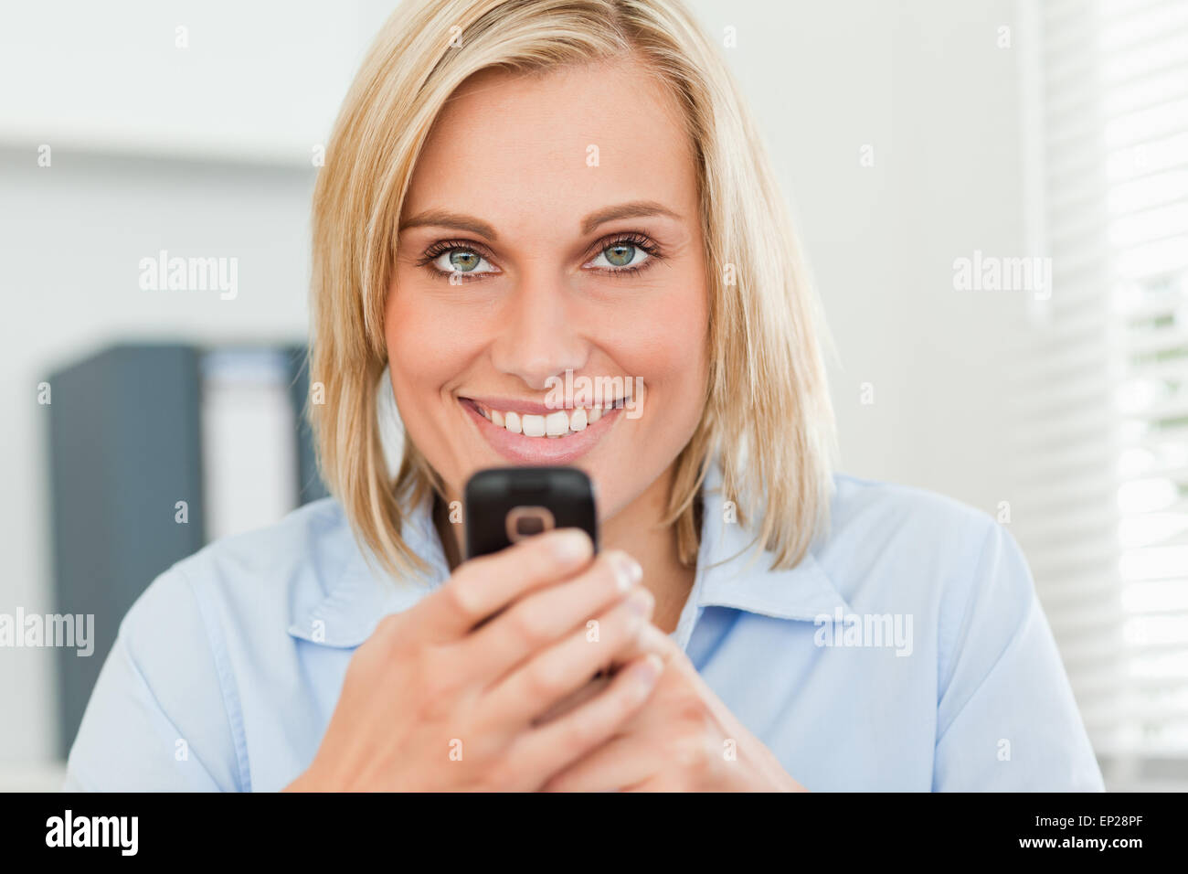 Smiling woman with mobile looking into camera Stock Photo - Alamy