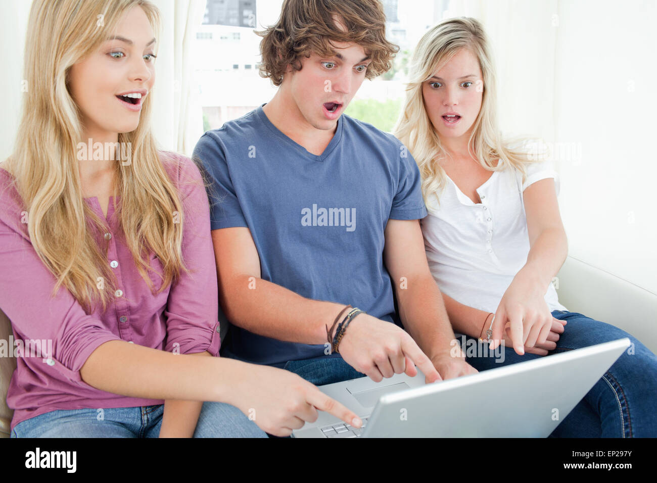 three friends shocked at what is on the laptop screen Stock Photo - Alamy