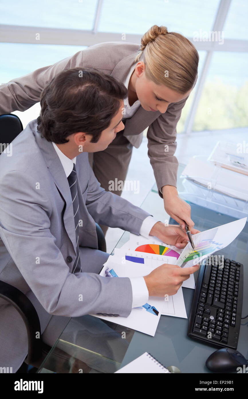 Portrait of a manager pointing at something to her employee on a graph ...