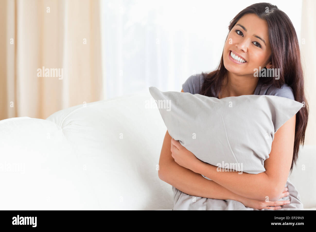 charming woman with pillow in her arms looking into camera Stock Photo ...