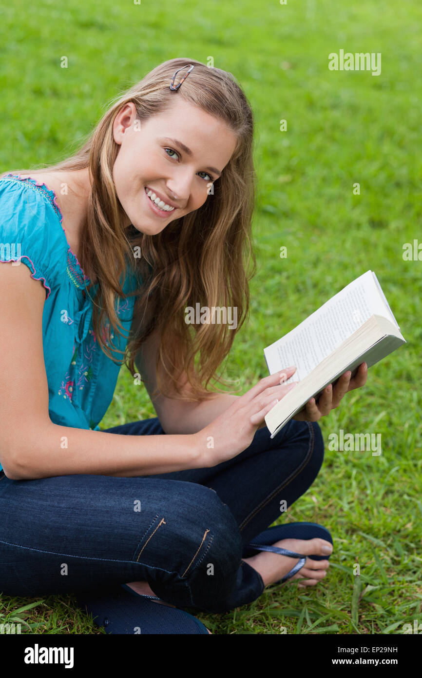Young smiling woman looking at the camera while reading a book Stock ...