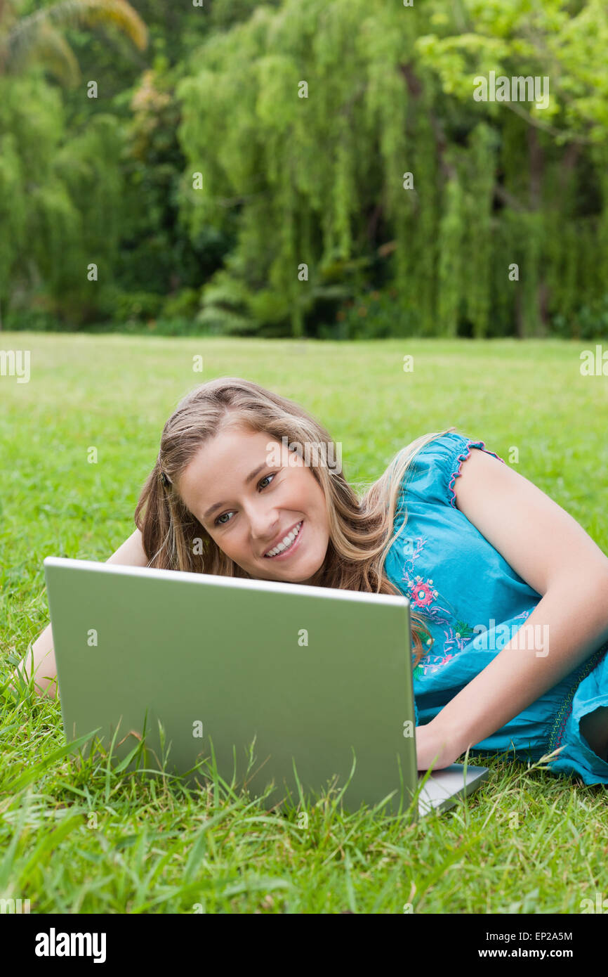 Young woman showing a great smile while lying on the side in a park ...