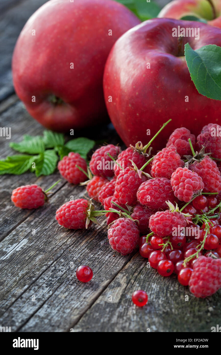 Redcurrant, raspberry and red apples on old wooden table, mix of red ...