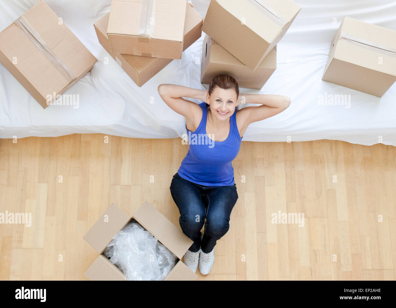 Beautiful woman sitting between boxes at home Stock Photo - Alamy