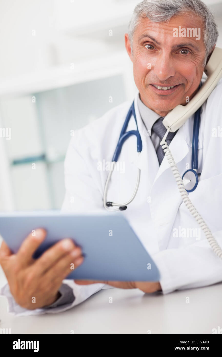 Smiling doctor holding a tablet computer and calling Stock Photo - Alamy