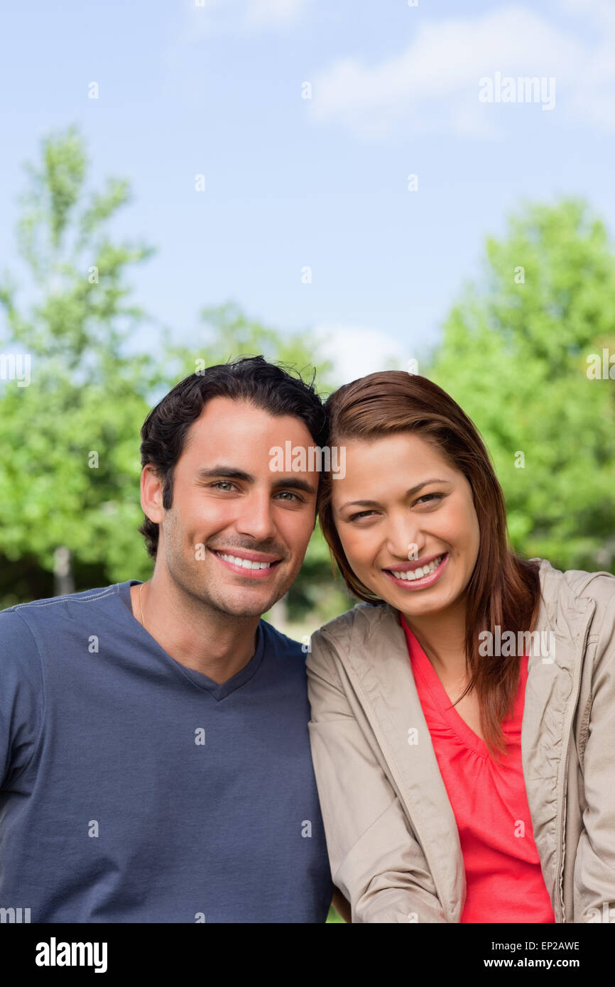Two friends smiling as the look ahead while leaning against each other ...