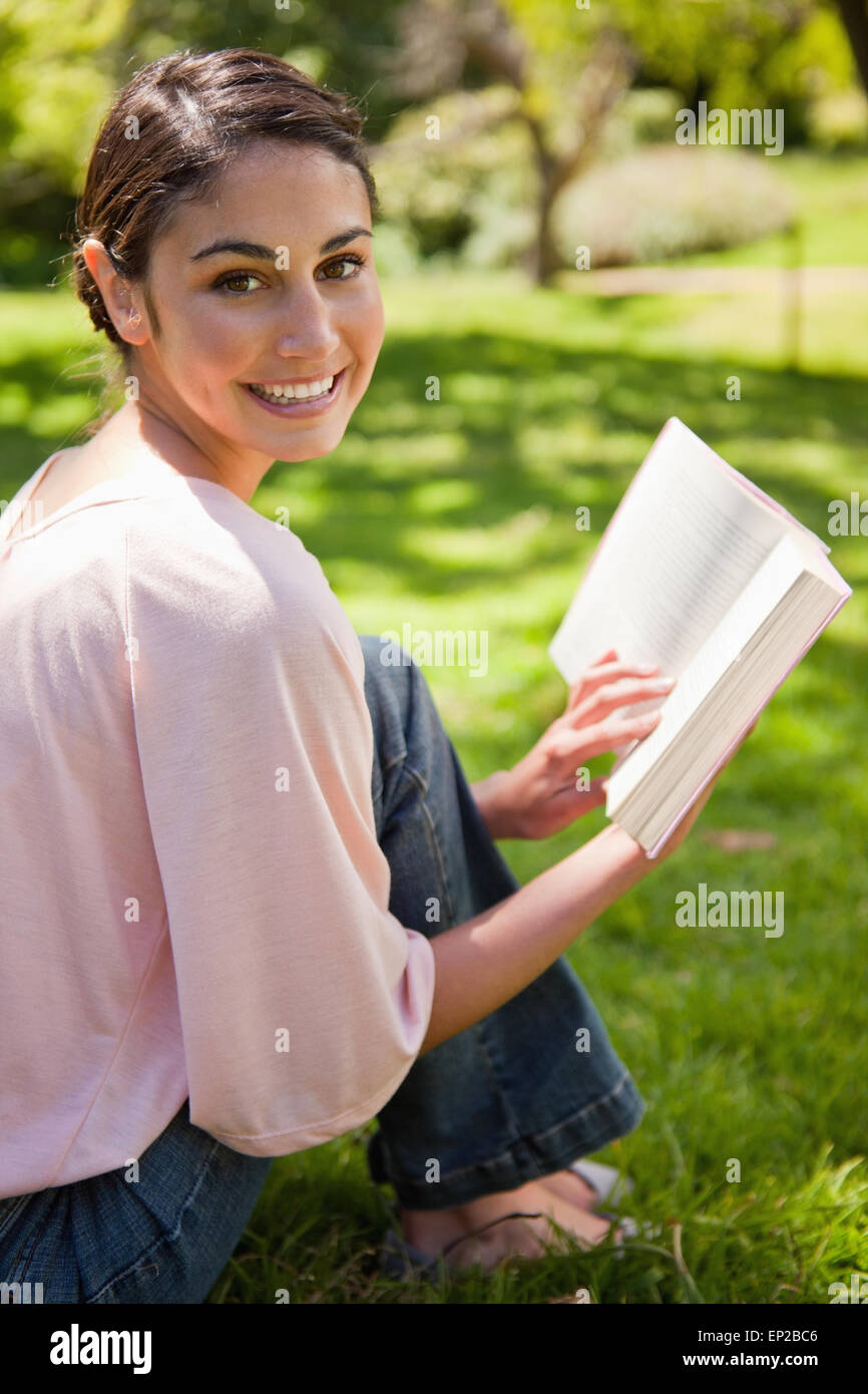 Woman looks to her side while reading a book in a park Stock Photo - Alamy