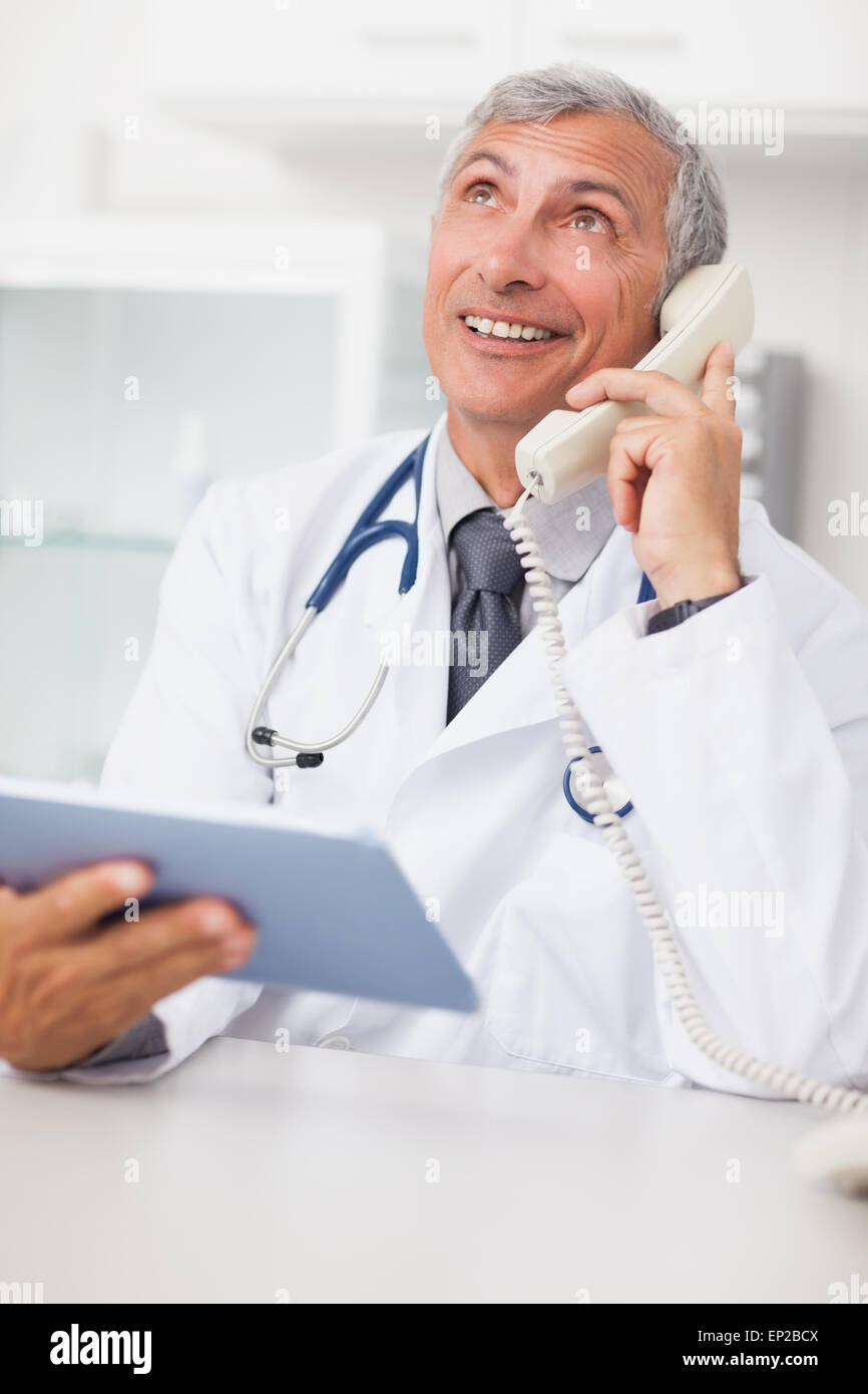 Doctor calling while holding a tablet computer Stock Photo - Alamy