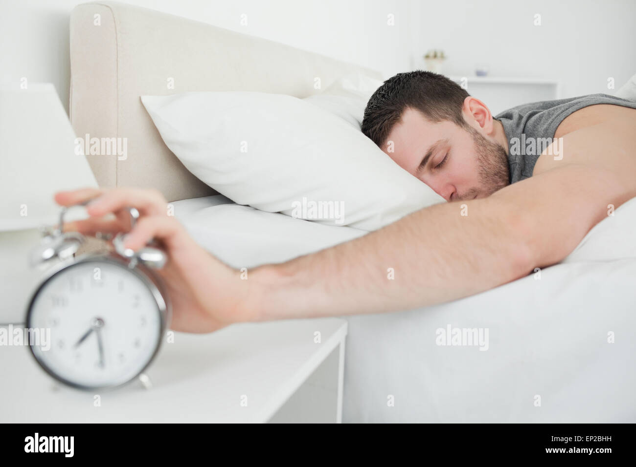 Sleeping handsome man being awakened by an alarm clock Stock Photo - Alamy
