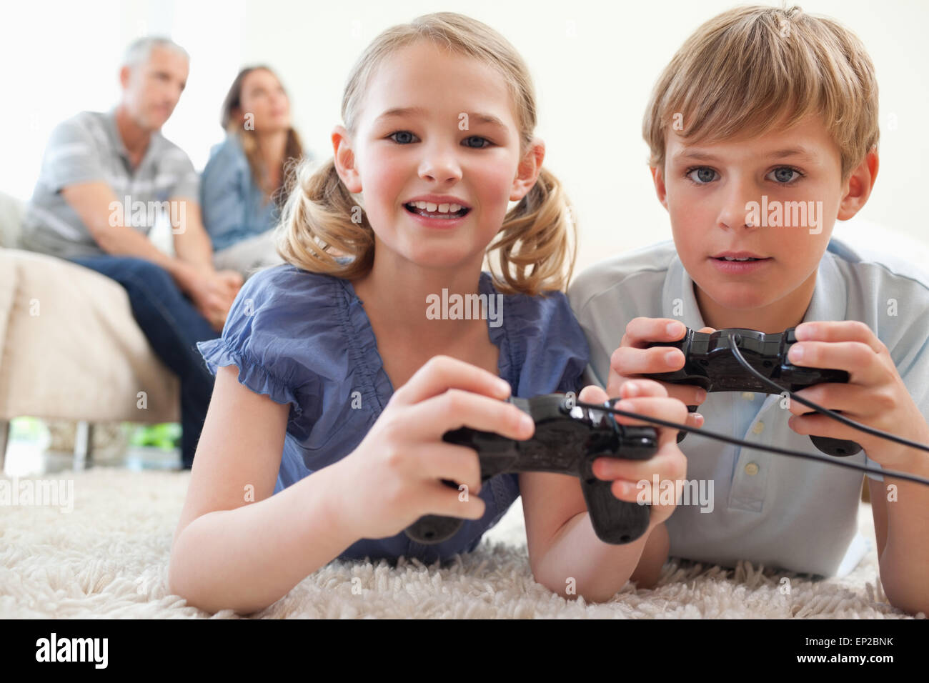 Playful siblings playing video games with their parents on the b Stock ...