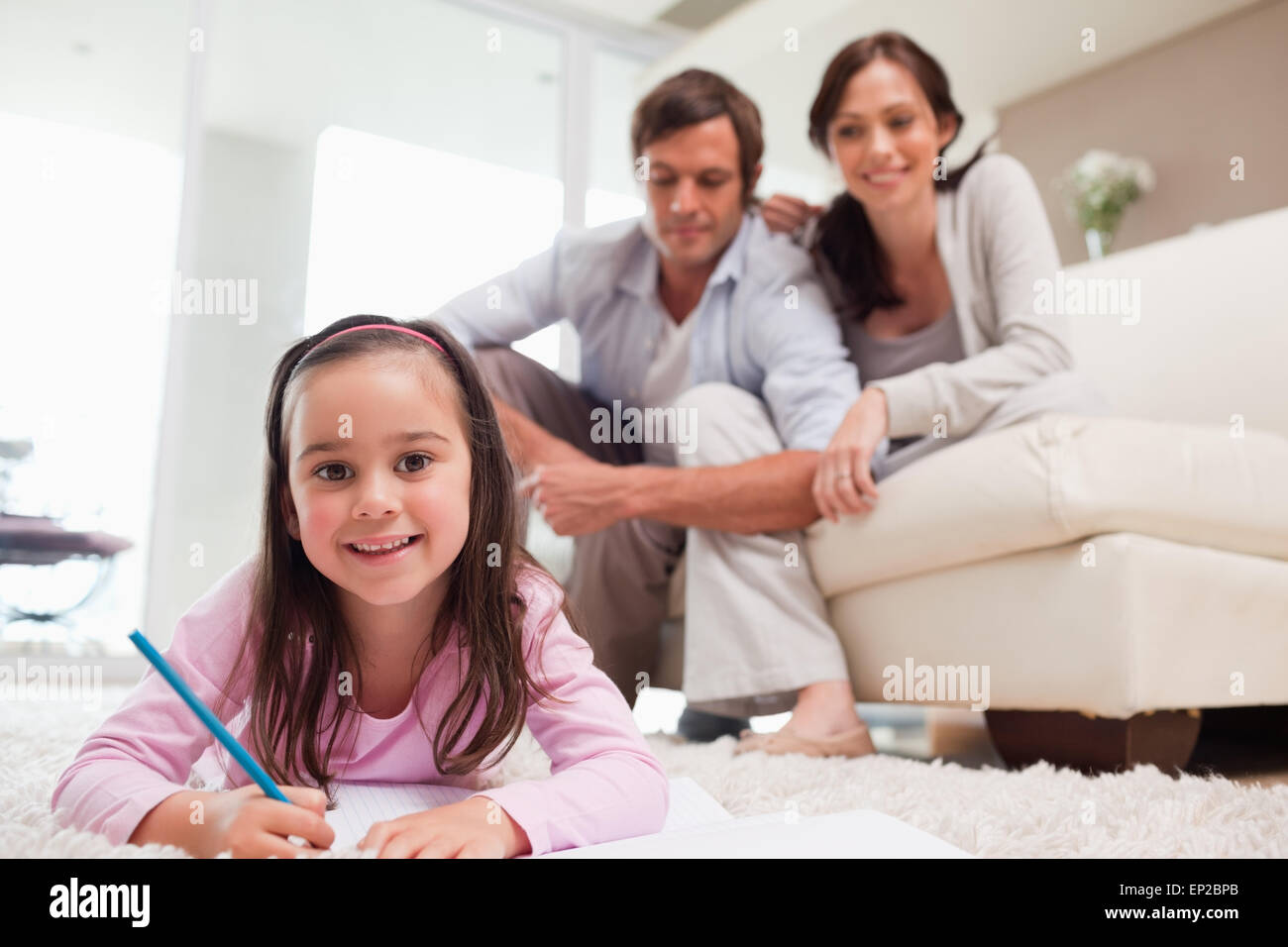 Girl drawing with her parents in the background Stock Photo - Alamy