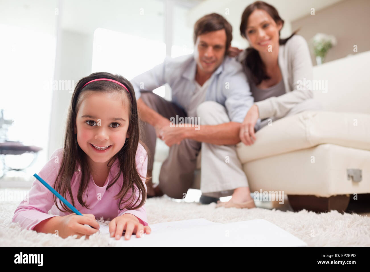Cute girl drawing with her parents in the background Stock Photo - Alamy