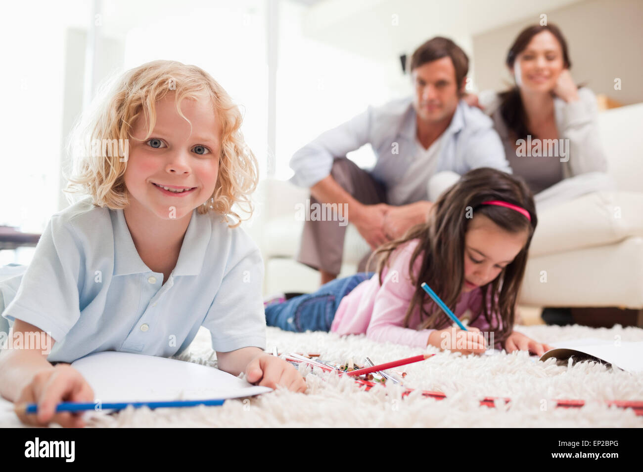 Children drawing while their parents are in the background Stock Photo ...