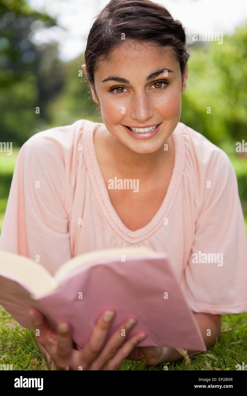 Woman looking ahead while reading a book as she is lying down Stock ...
