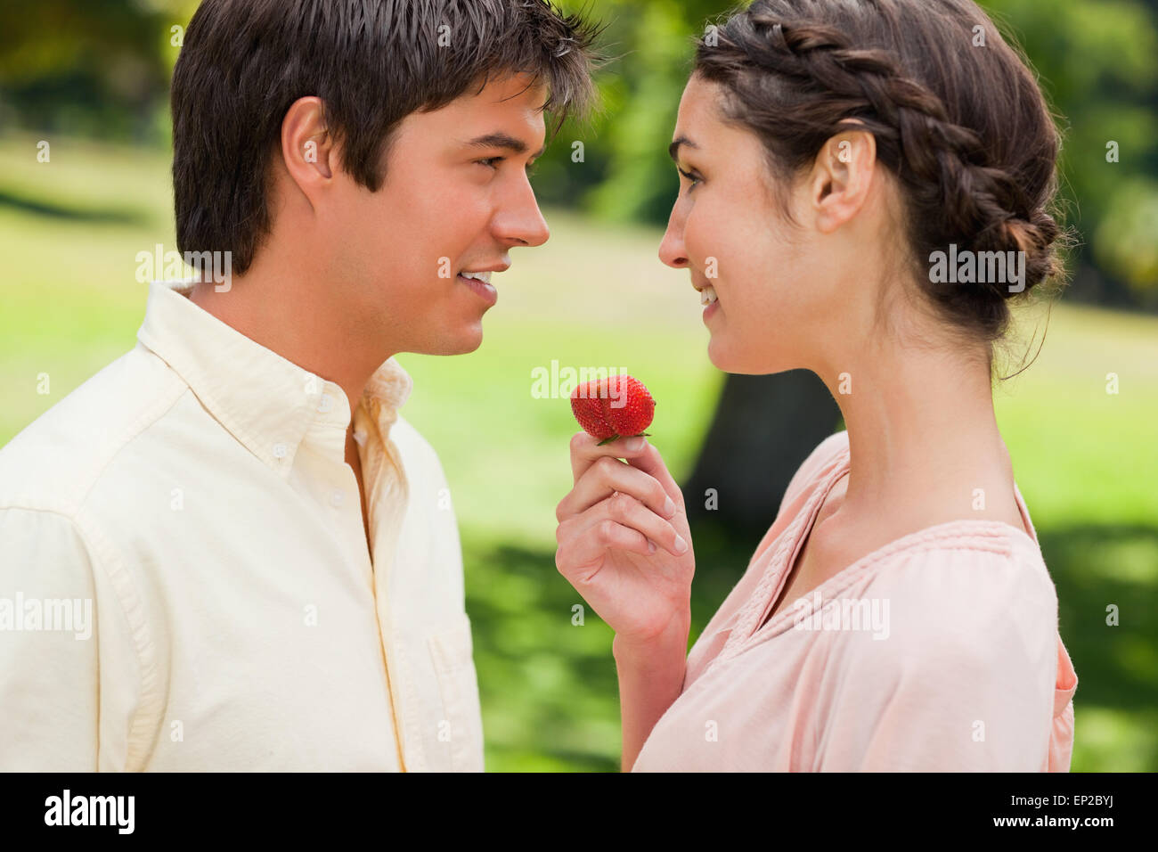 Man smiling while being offered a strawberry by his friend Stock Photo ...