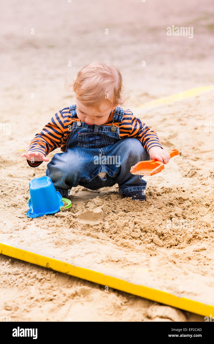 Cute baby boy playing with sand in a sandbox Stock Photo - Alamy