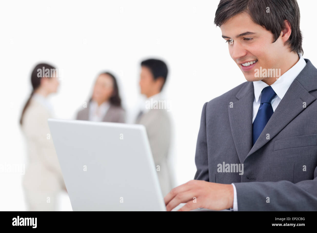 Salesman with laptop and colleagues behind him Stock Photo - Alamy