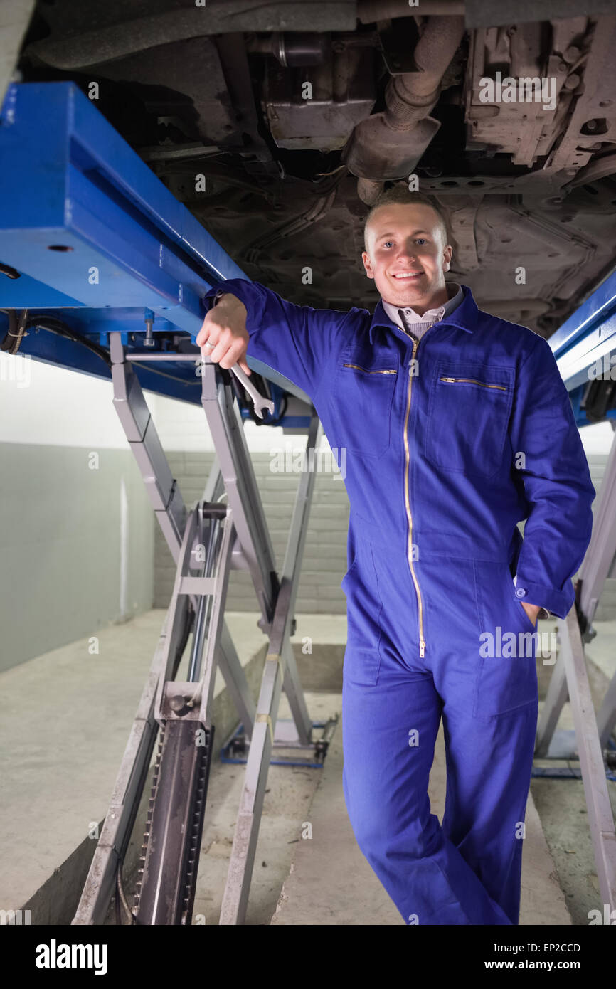 Mechanic leaning on a machine while holding a spanner Stock Photo - Alamy
