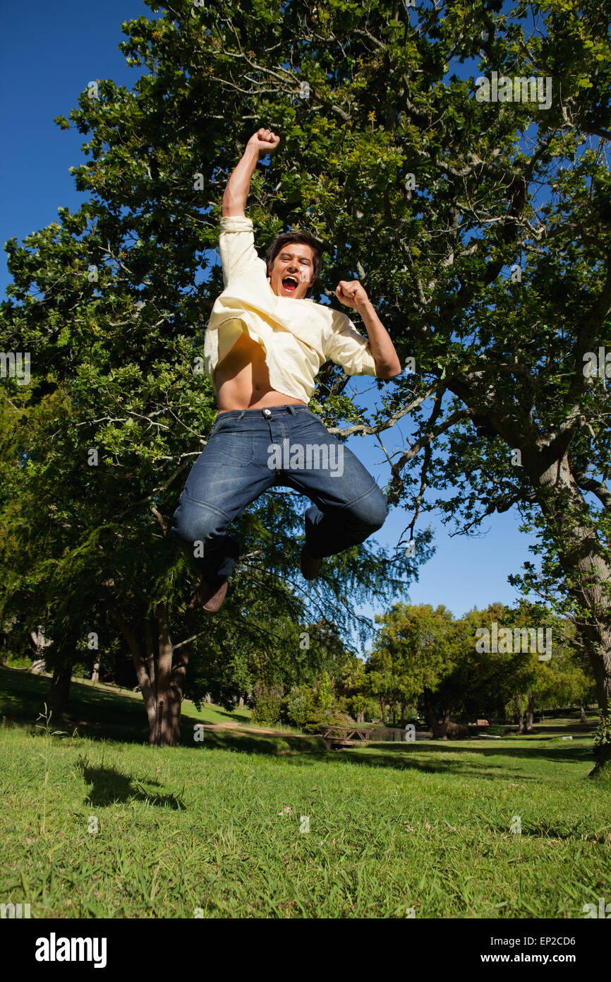 Man looking down to the ground as he jumps with his arms raised in ...