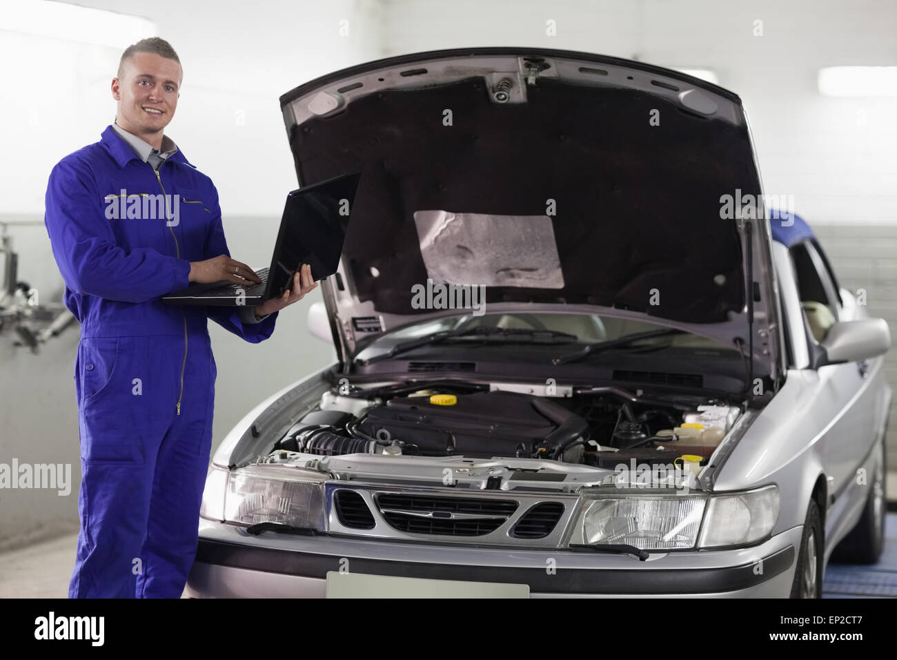 Mechanic typing on a computer while looking at camera Stock Photo - Alamy