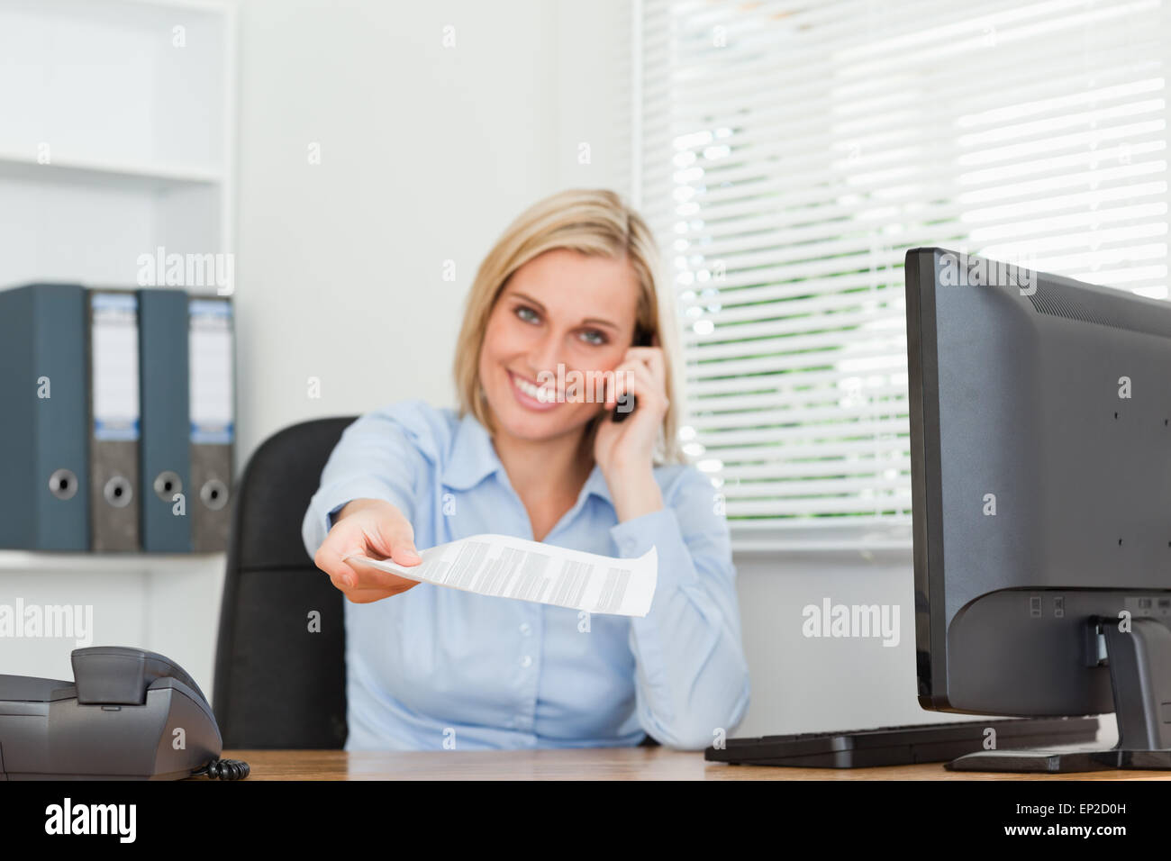Businesswoman phoning and passing a paper looks into camera Stock Photo ...