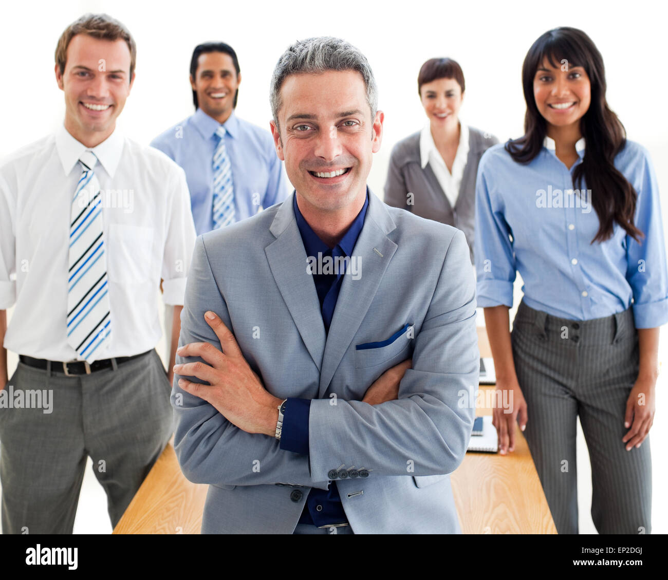Smiling manager with folded arms in front of his team Stock Photo - Alamy