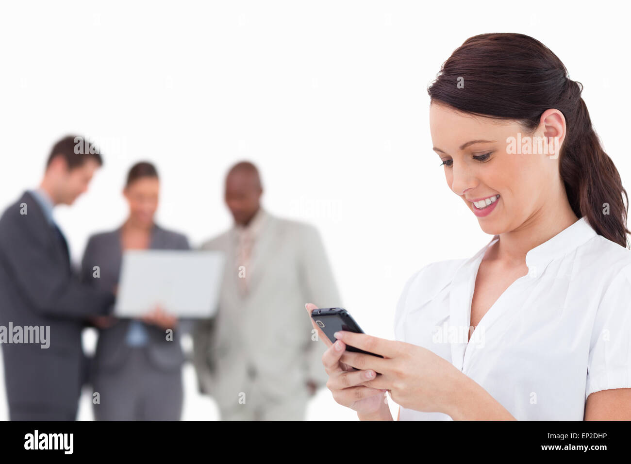 Businesswoman writing text message with colleagues behind her Stock ...