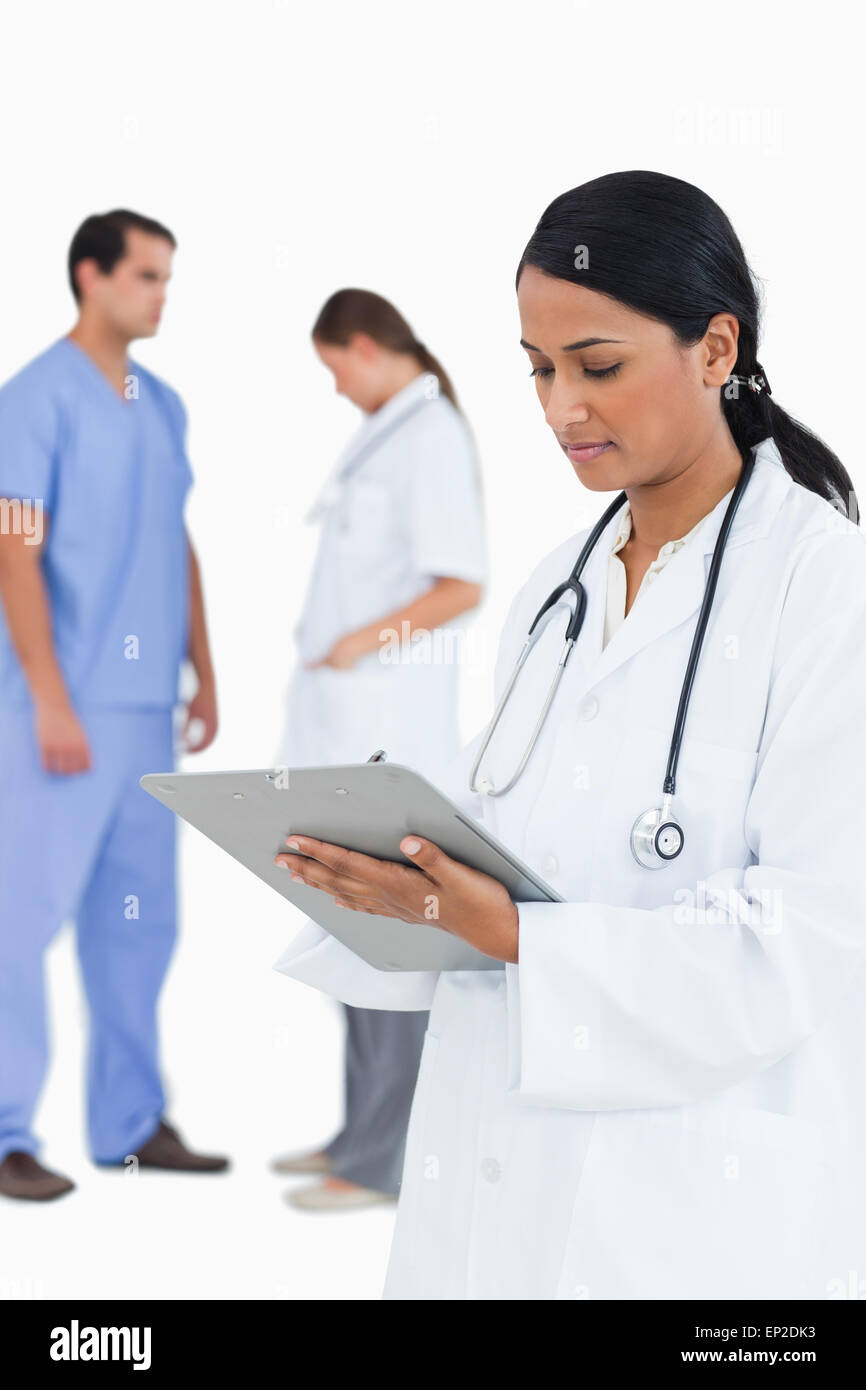 Doctor taking notes with staff members behind her Stock Photo - Alamy